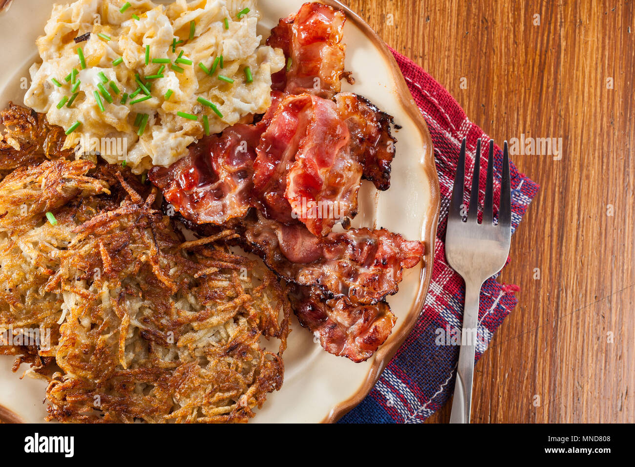 Hash browns. Potato pancakes with crispy fried bacon and scrambled eggs ...