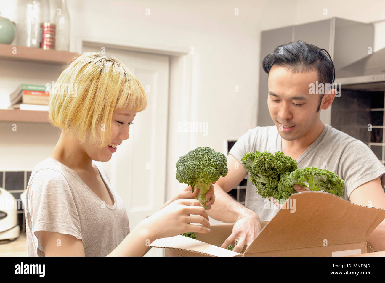 Smiling young couple removing fresh vegetables from cardboard box Stock ...
