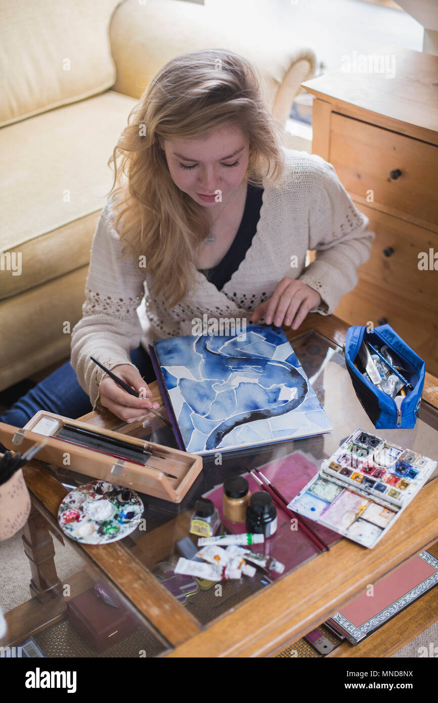 High angle view of young woman making painting while sitting in living ...