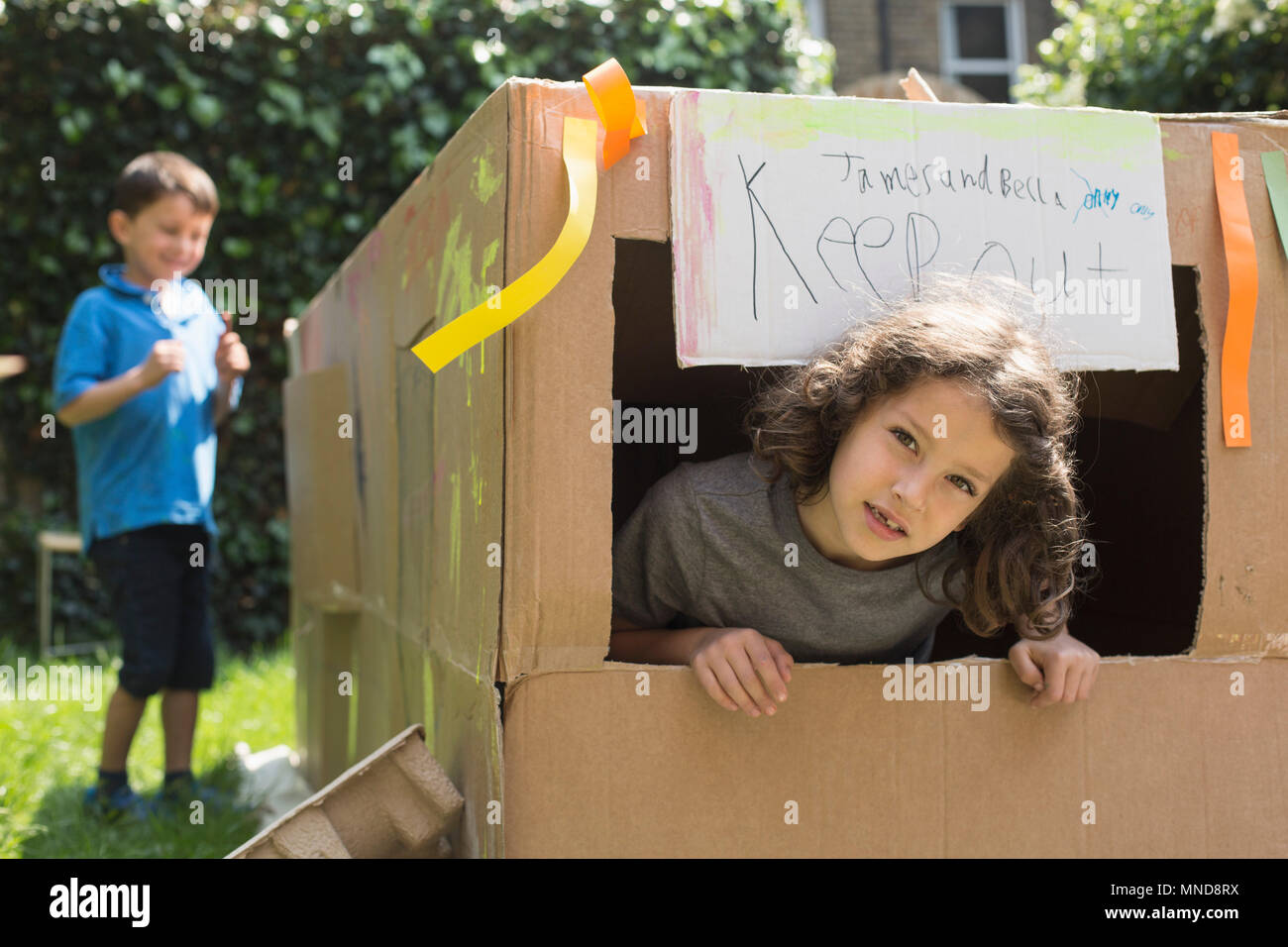 Portrait of cute girl in cardboard playhouse at back yard Stock Photo ...