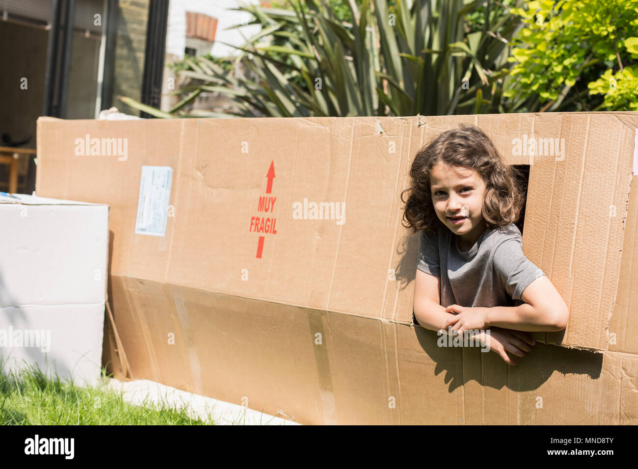Portrait of girl in cardboard playhouse at back yard on sunny day Stock ...