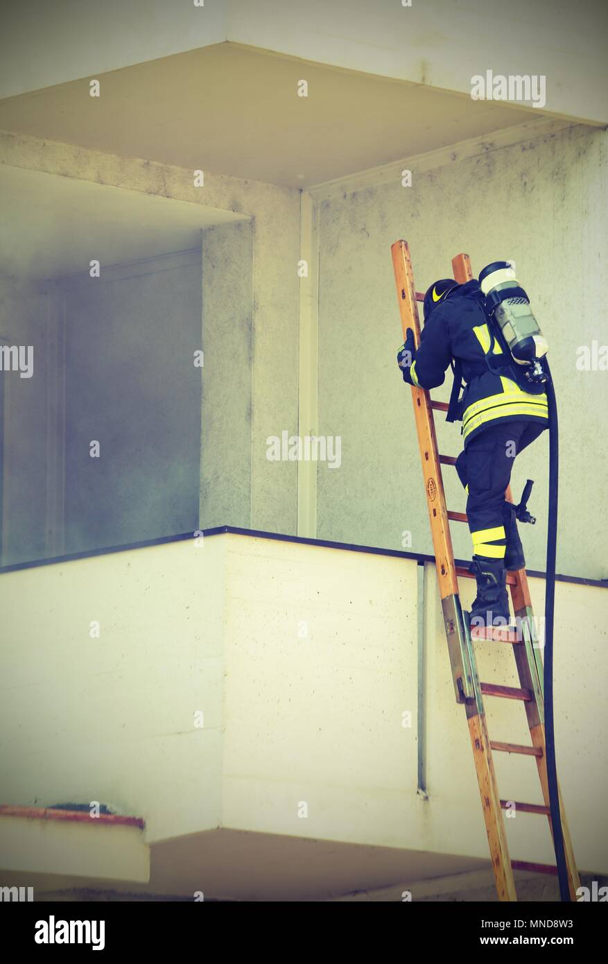 Firefighter with oxygen cylinder climbing a wooden ladder with vintage ...