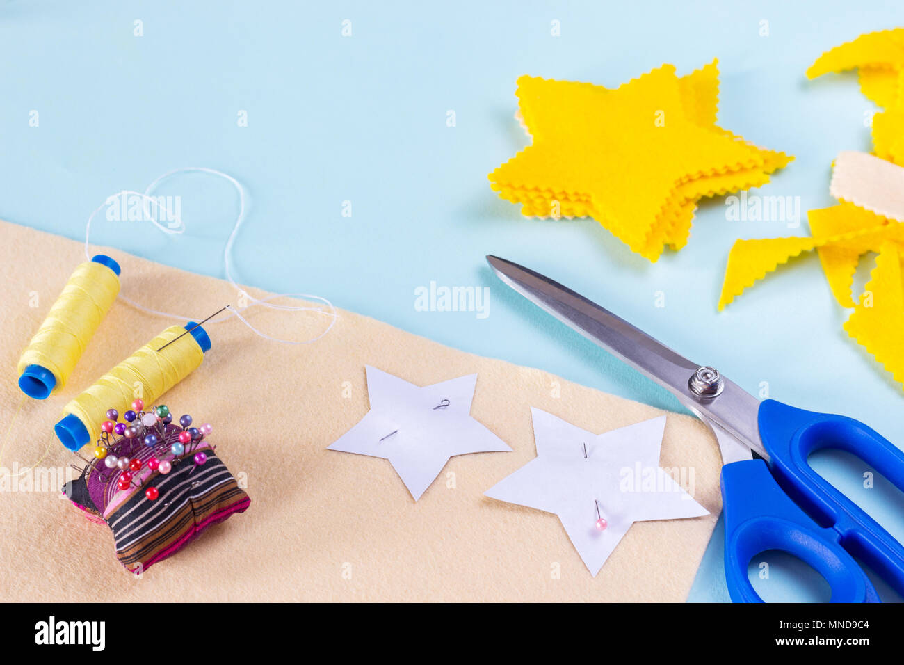 sewing star figures from yellow felt, materials on a light blue ...