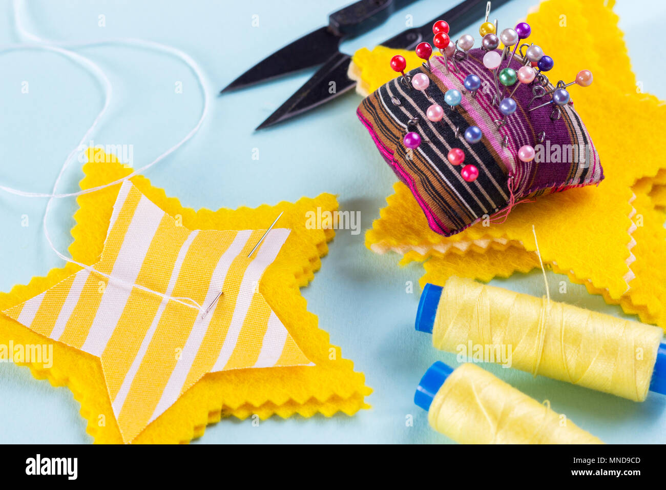 sewing star figures from yellow felt, materials on a light blue ...
