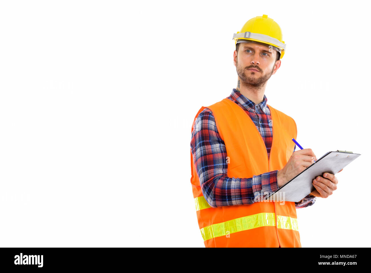 Studio shot of young man construction worker writing on clipboard while ...