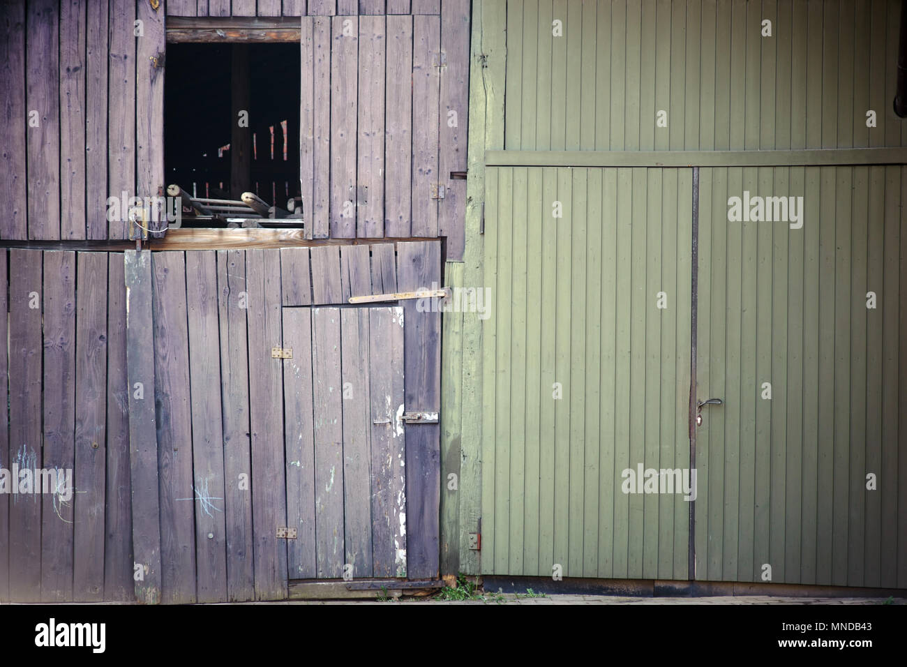 An old shaky and faded barn door with an entrance door and an open ...