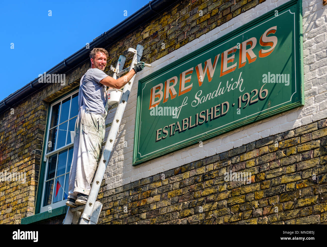 Pianter and decorator painting around a shop sign Stock Photo - Alamy