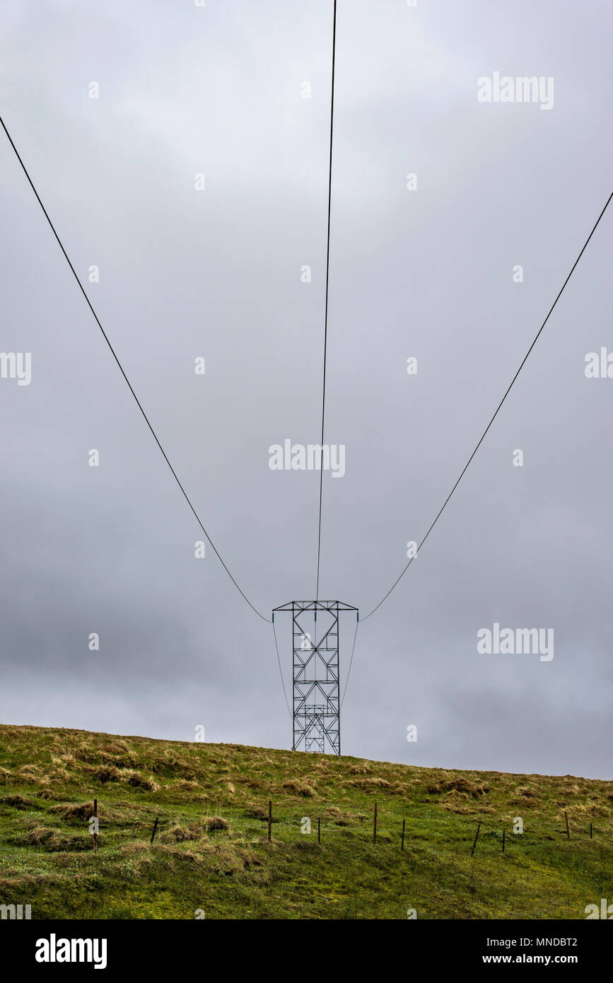 Low angle view of electricity pylon on green field against cloudy sky ...
