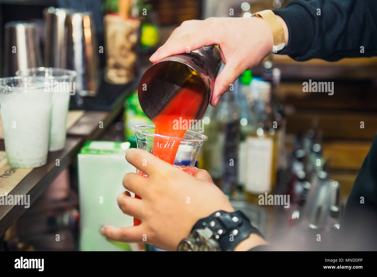 Expert pro barman is making cocktail and pouring drink into a plastic ...