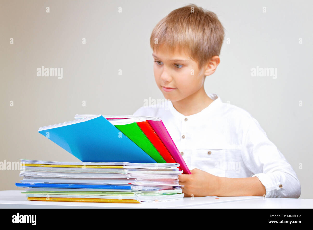 Child doing his homework at home. The boy sitting and looking in to ...