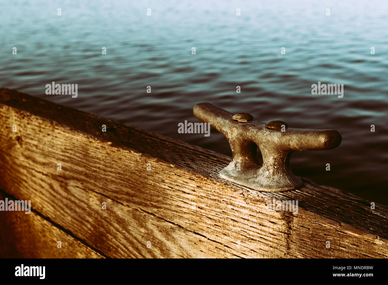 Nautical cleat on pier closeup with water background Stock Photo - Alamy