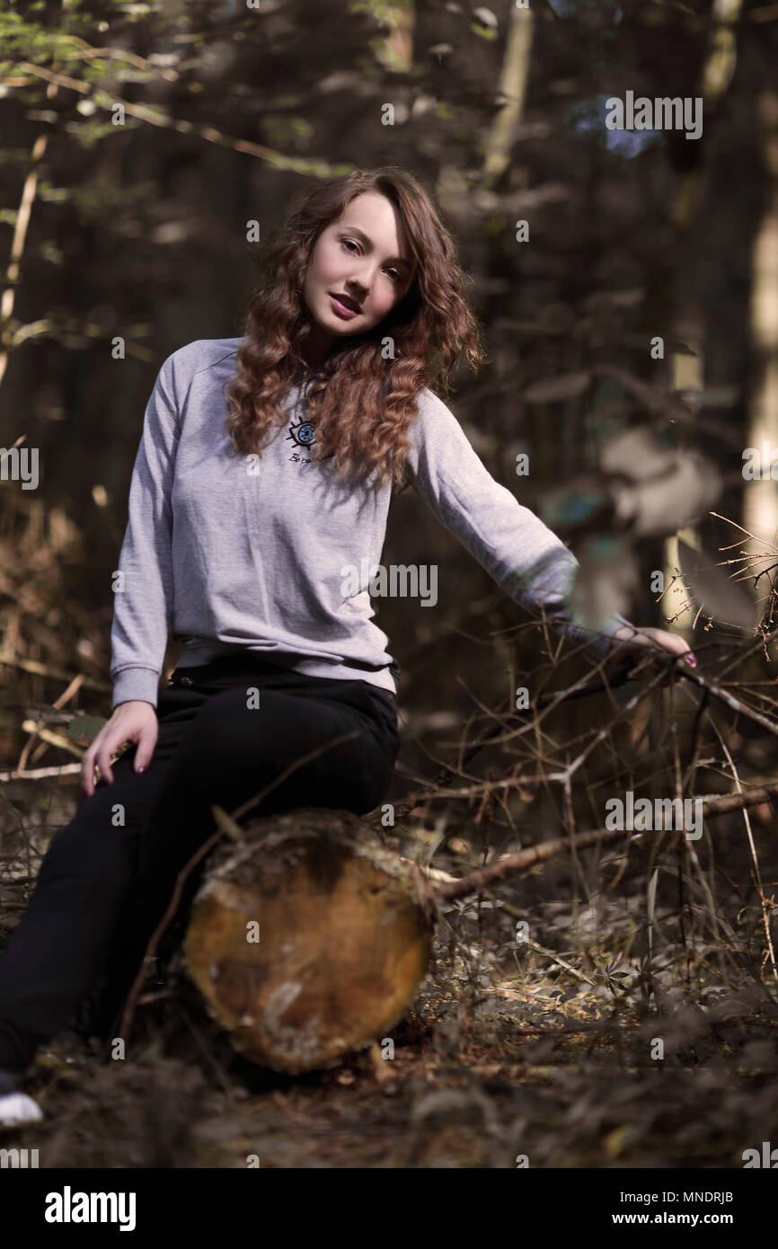 beautiful young woman sitting on a log Stock Photo - Alamy