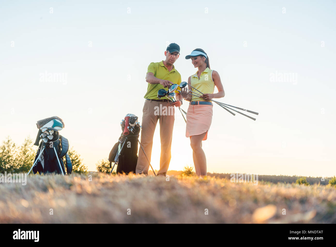 Golf instructor teaching a young woman how to use different golf clubs ...