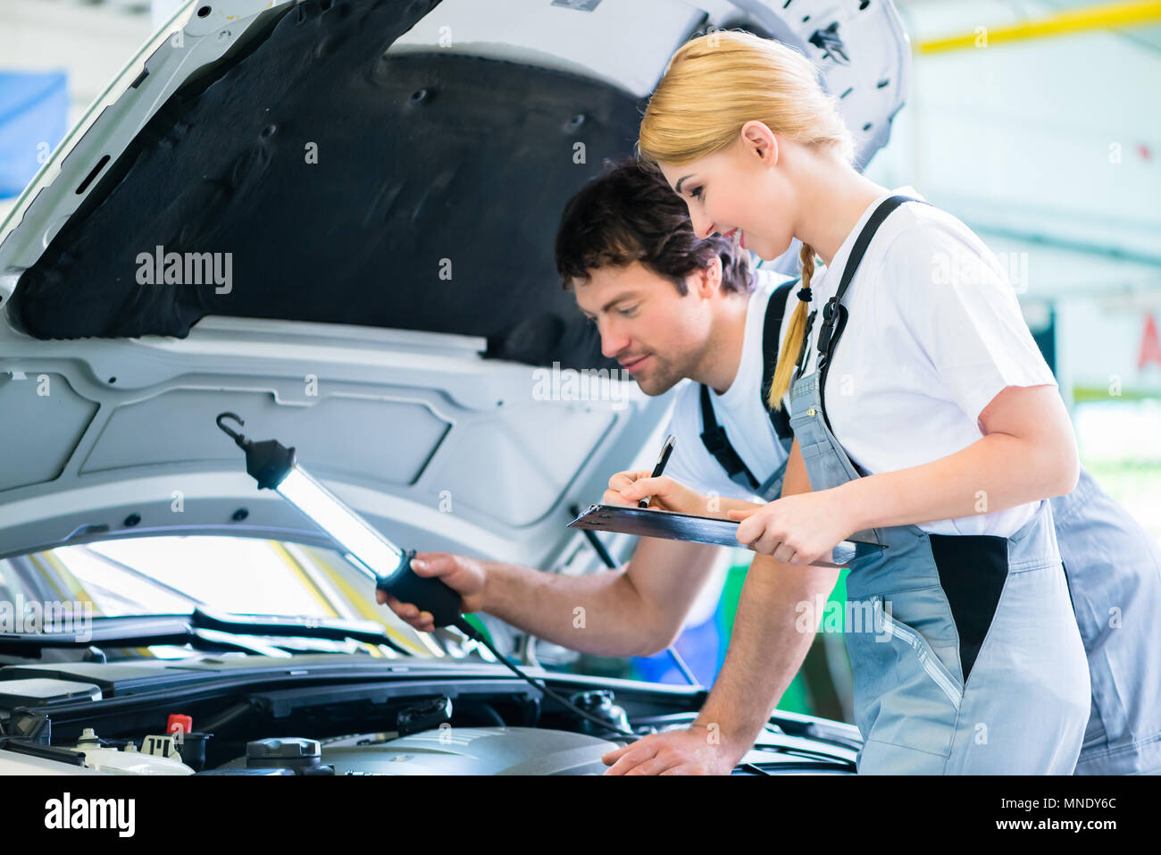 Mechanic team working in car workshop Stock Photo - Alamy