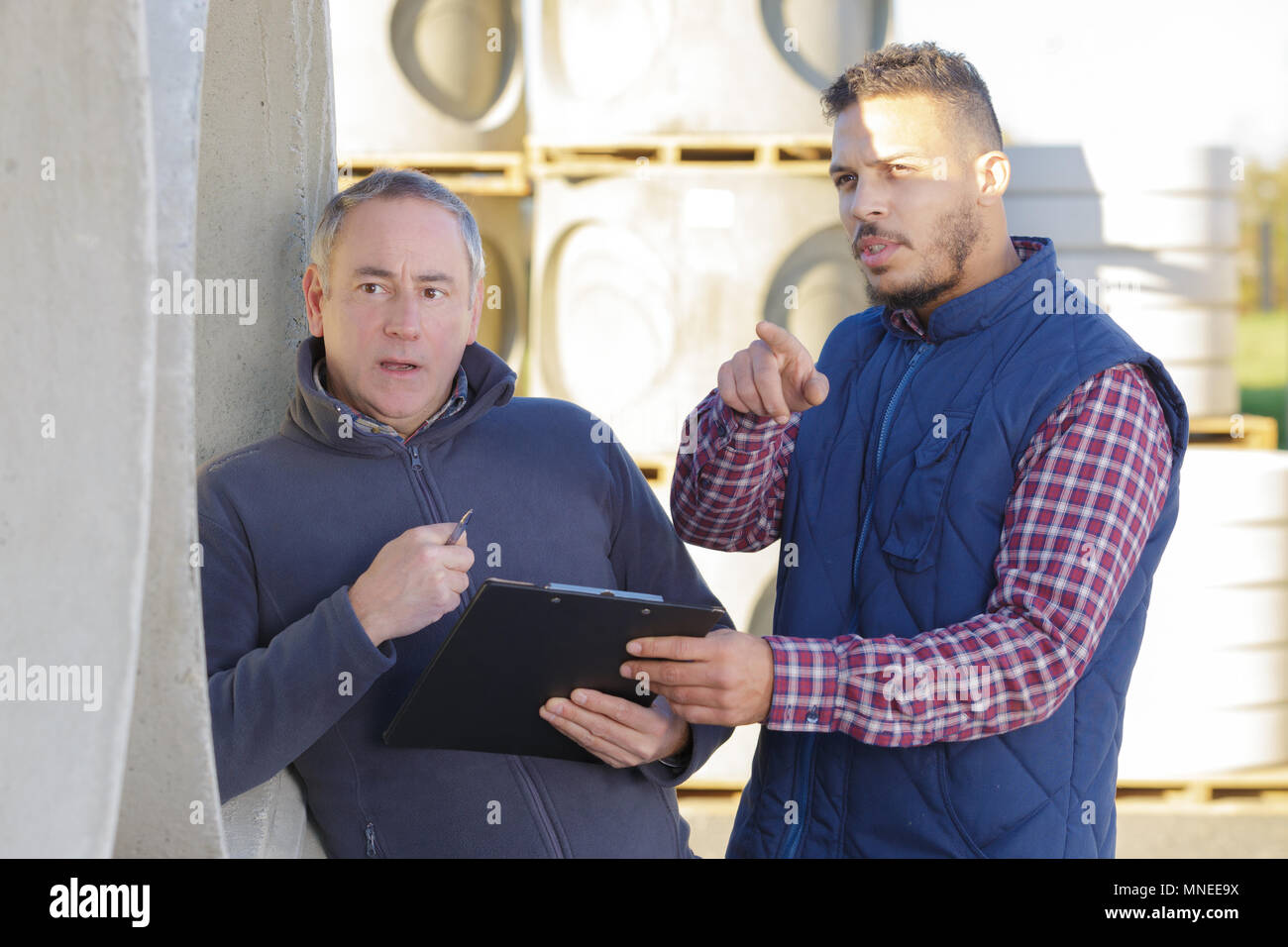 worker and engineer working outsude a factory pointing Stock Photo - Alamy