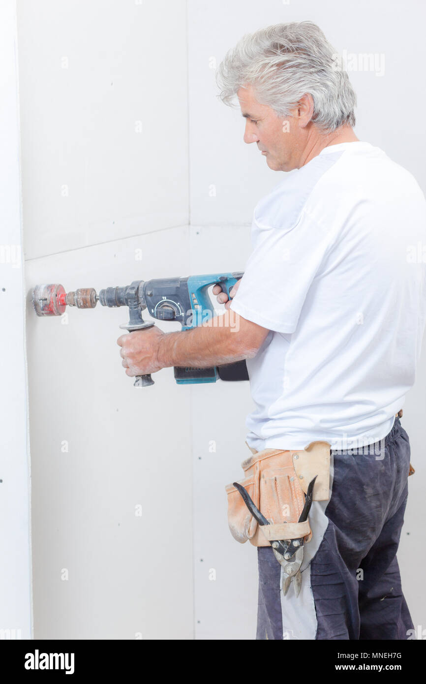 Builder using drill with attachment to make hole Stock Photo - Alamy