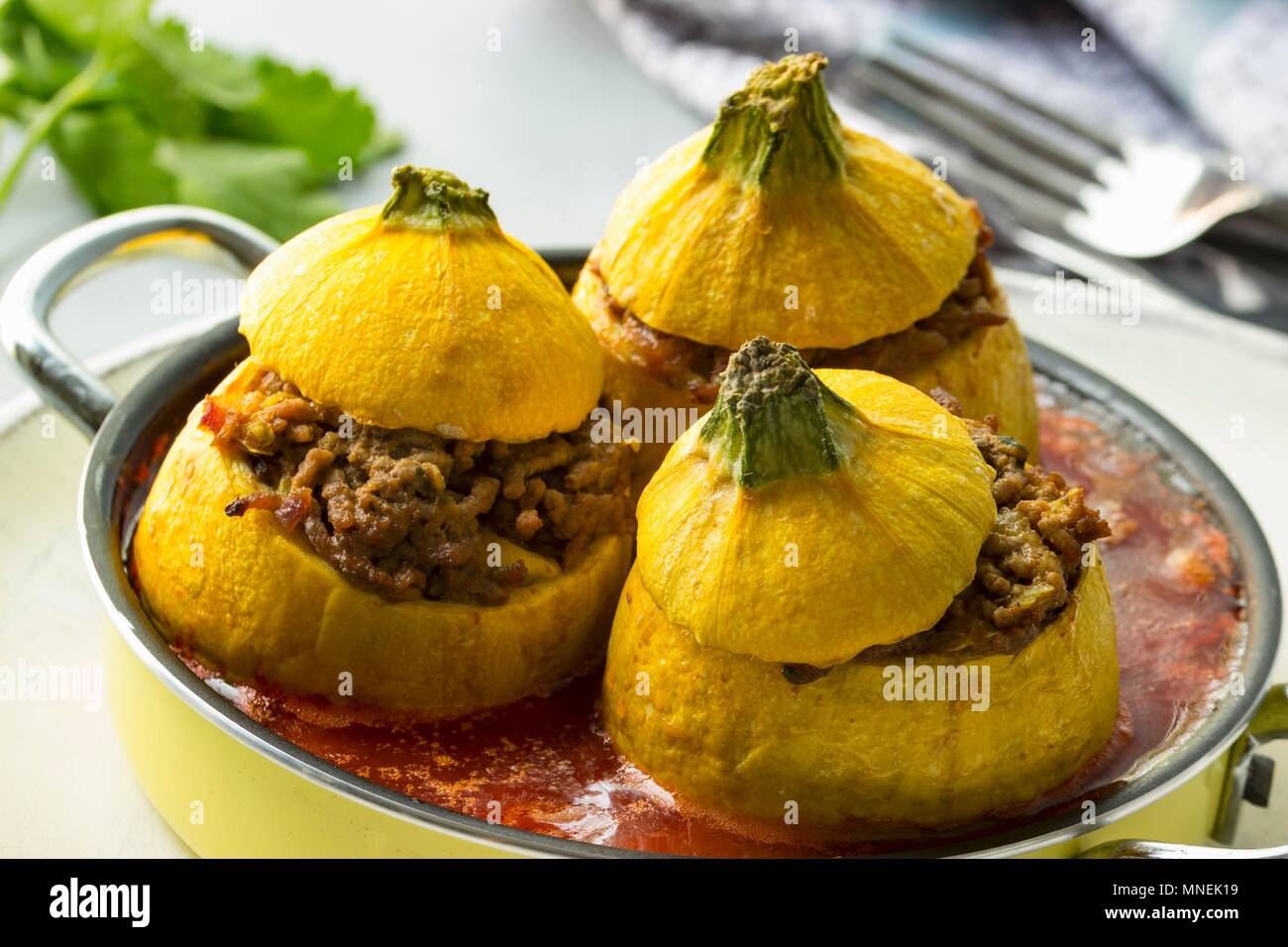 Yellow squash filled with minced meat and tomato sauce and cutlery ...