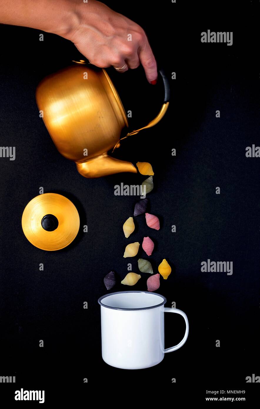Shell pasta being poured from a teapot into an enamel mug Stock Photo ...
