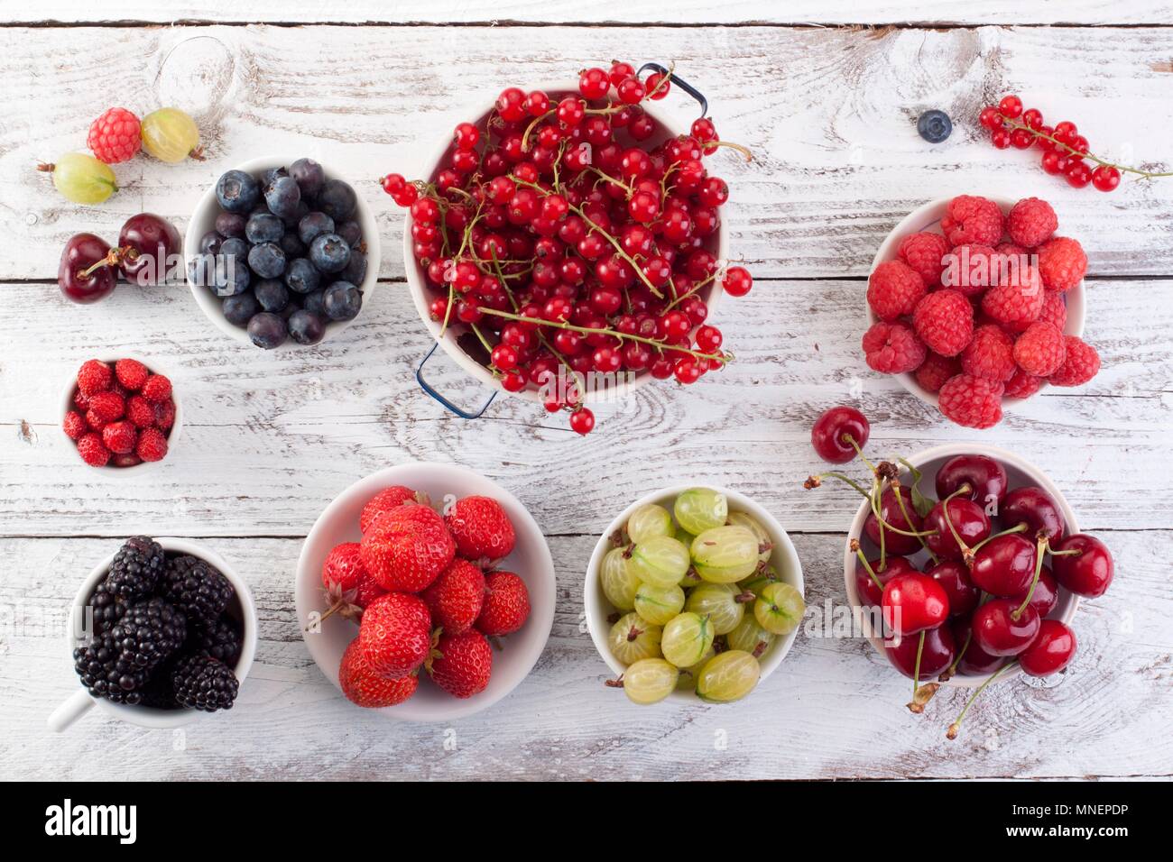 Fresh berries and cherries in bowls on a wooden surface Stock Photo - Alamy