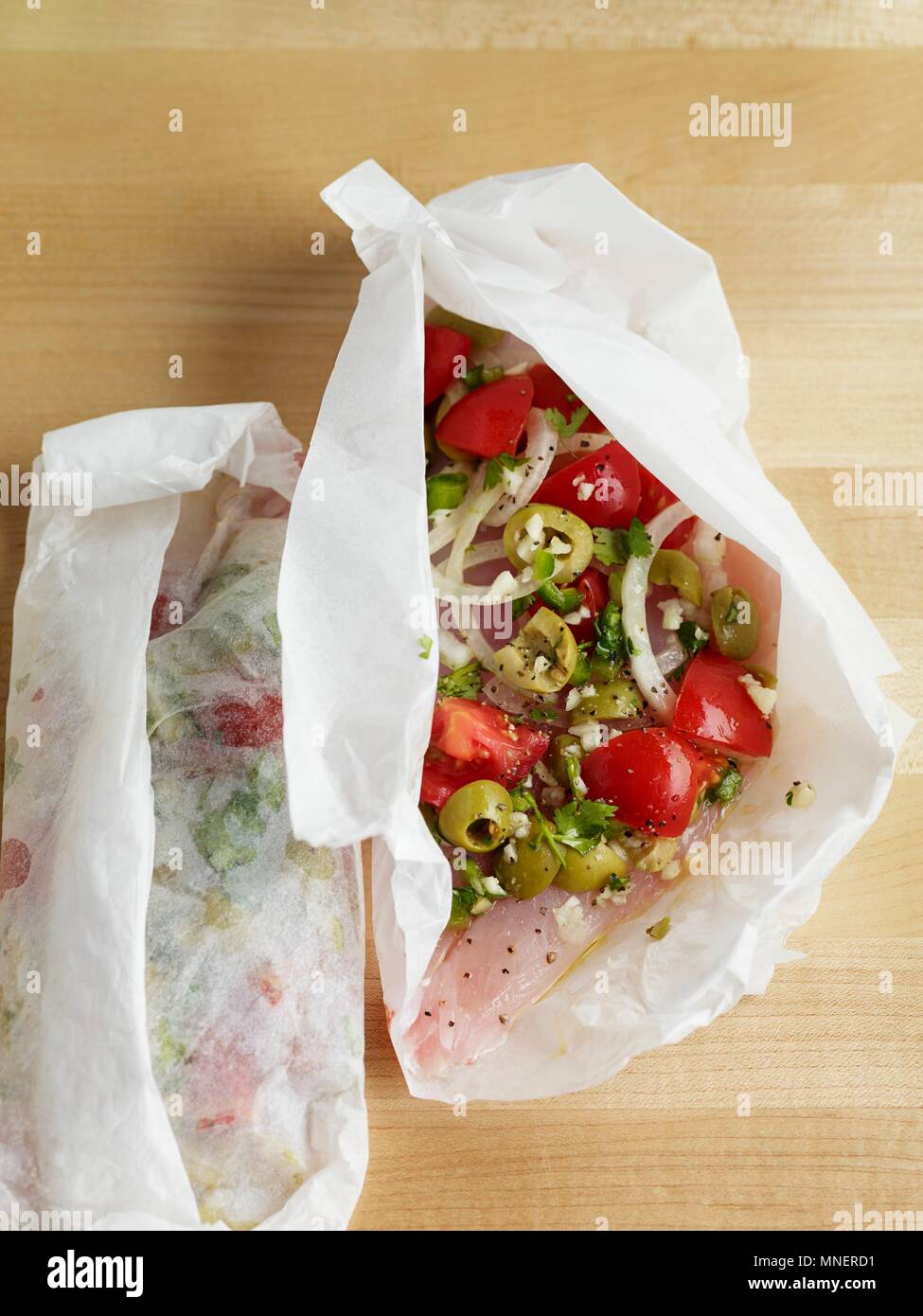 Fish fillet with tomatoes, olives and onions in parchment paper Stock ...