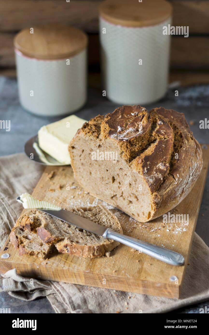 Homemade beer bread baked in a clay pot with butter on a wooden board ...