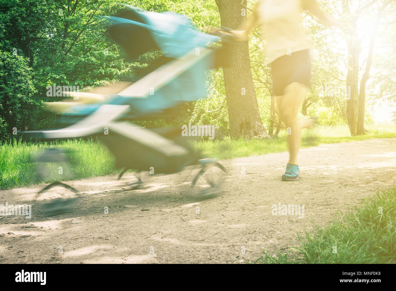 Running woman with baby stroller enjoying summer in park. Jogging or ...