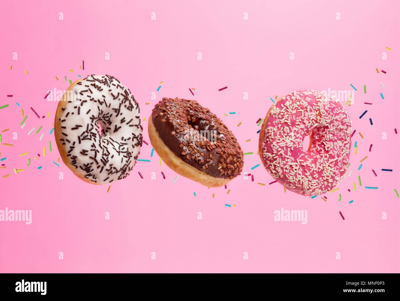 Flying sweet donuts isolated on pink background. Concept of low gravity ...