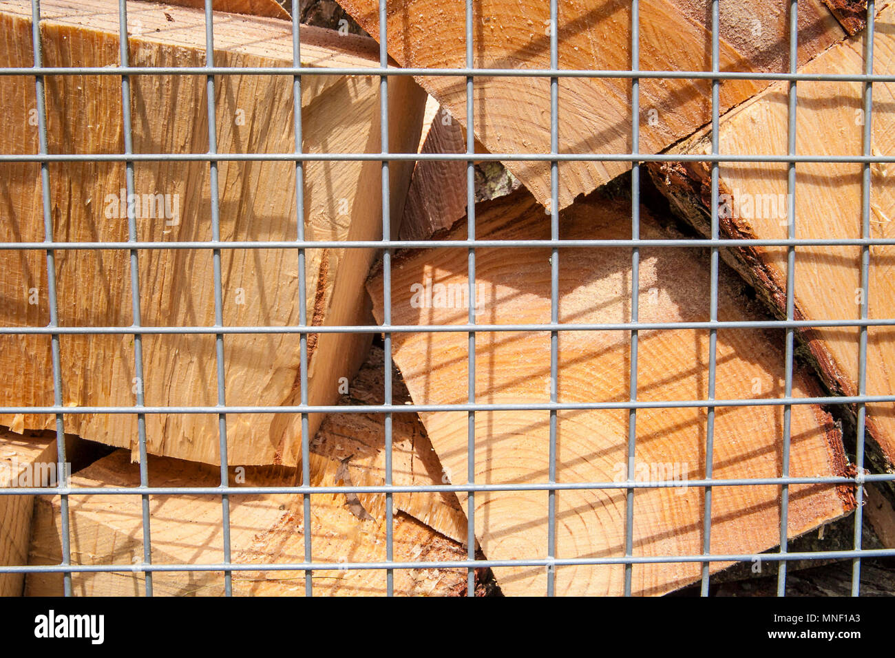Logs of pine wood in a wire container Stock Photo - Alamy