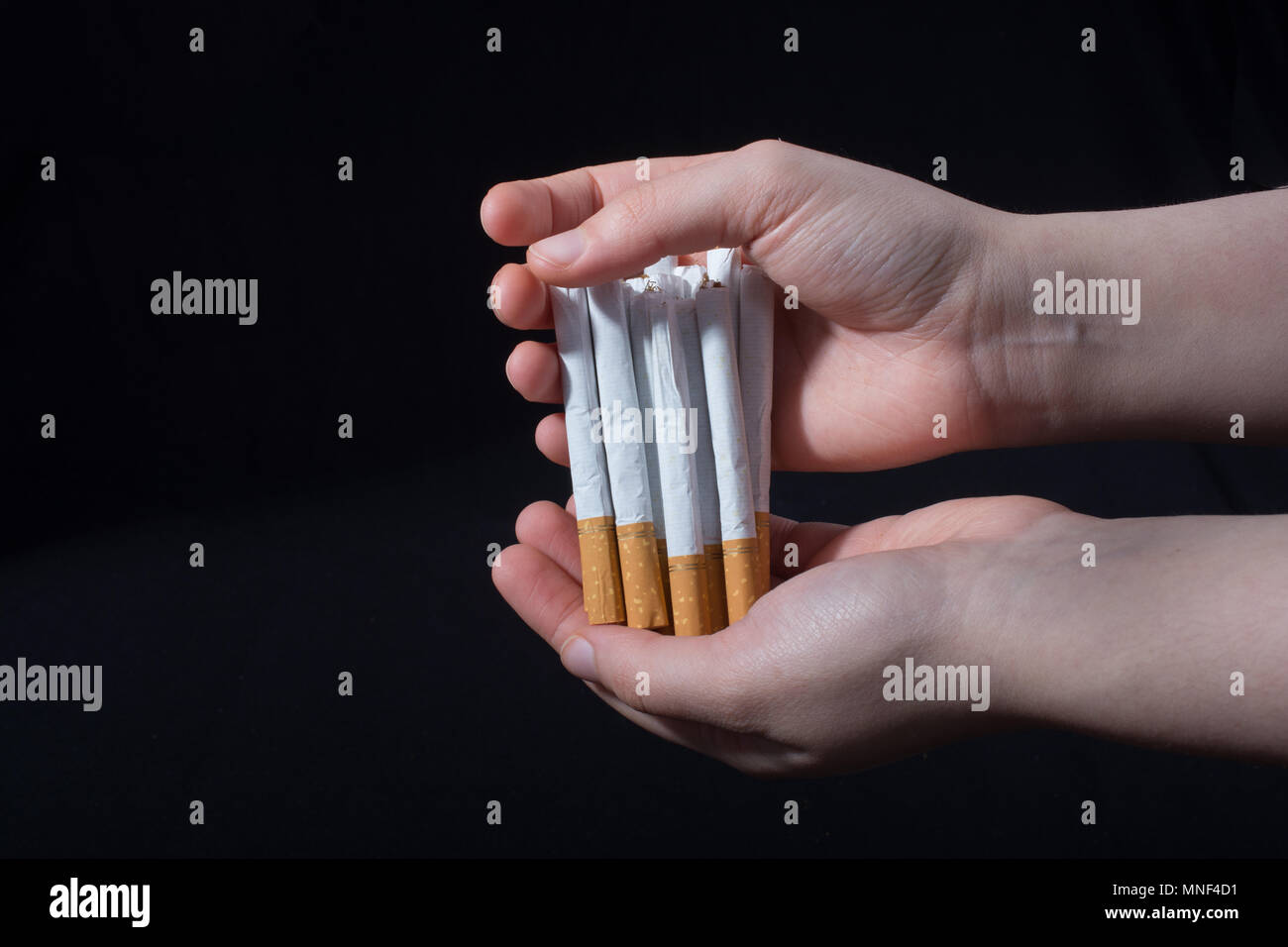 Hand is giving out bundle of cigarettes on black background Stock Photo ...