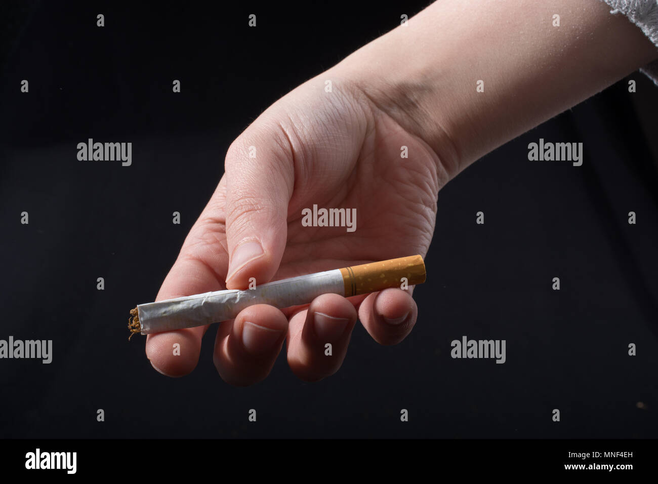 Hand is giving out cigarette on a black background Stock Photo - Alamy