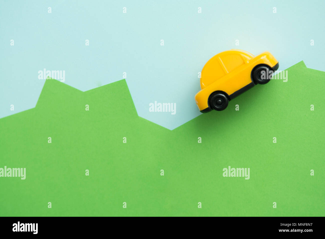 Yellow car driving over hills with blue sky background Stock Photo - Alamy
