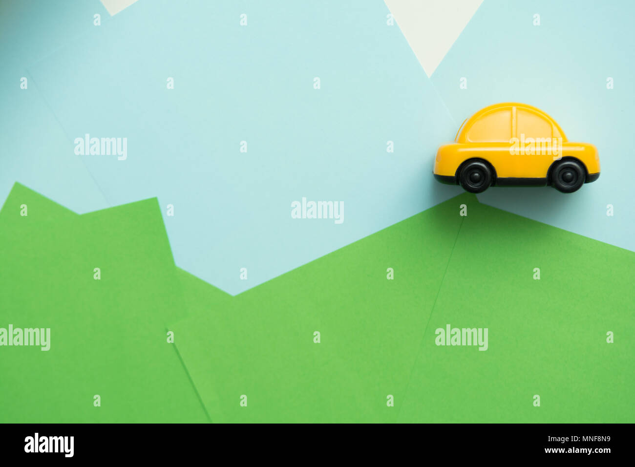 Yellow car driving over hills with blue sky background Stock Photo - Alamy