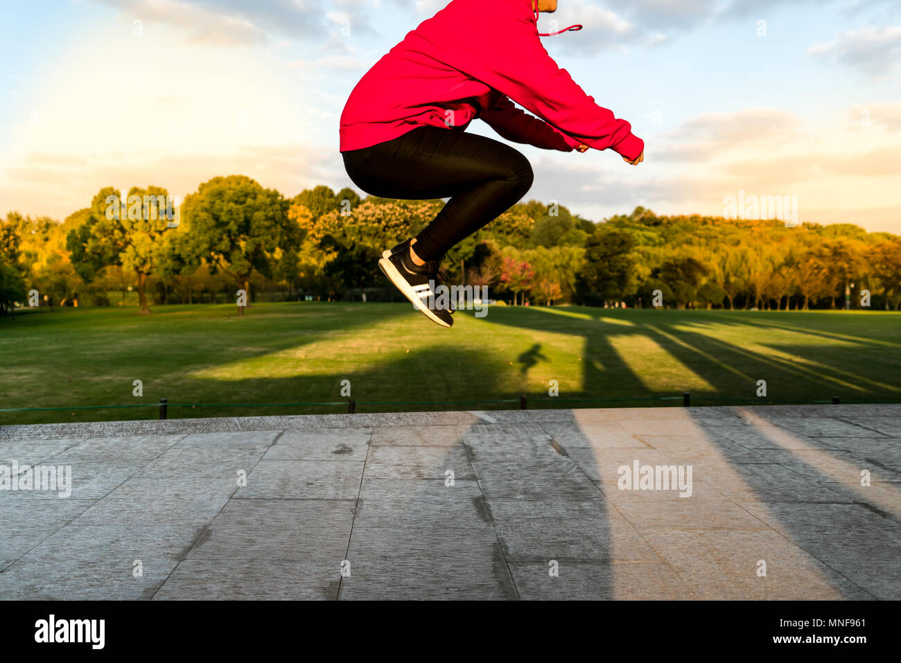 happy young woman is jumping over the garden with overexposure and ...