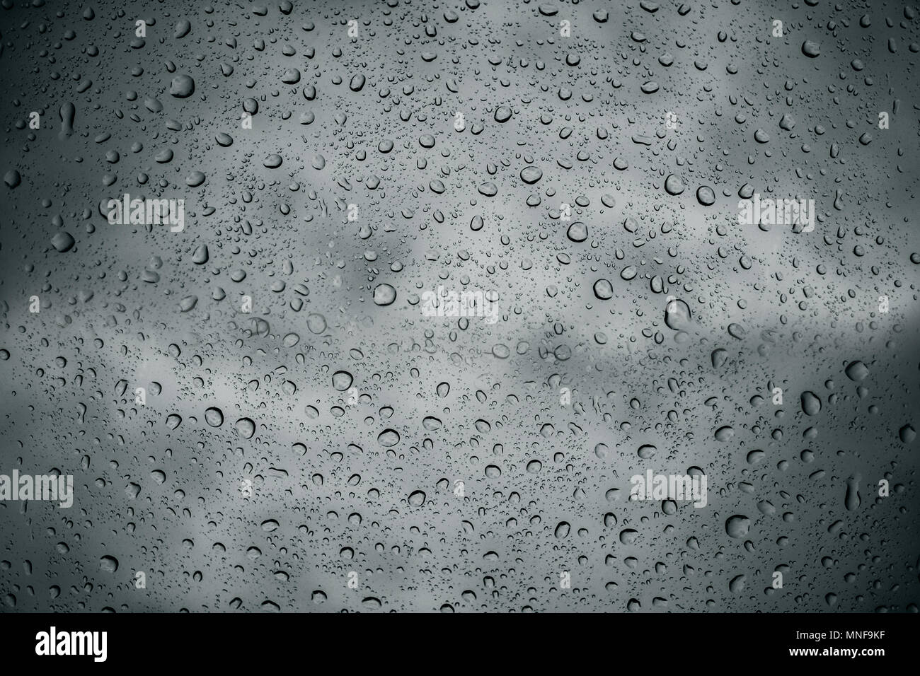 Water drops on transparent glass window and cloudy dark sky after storm ...