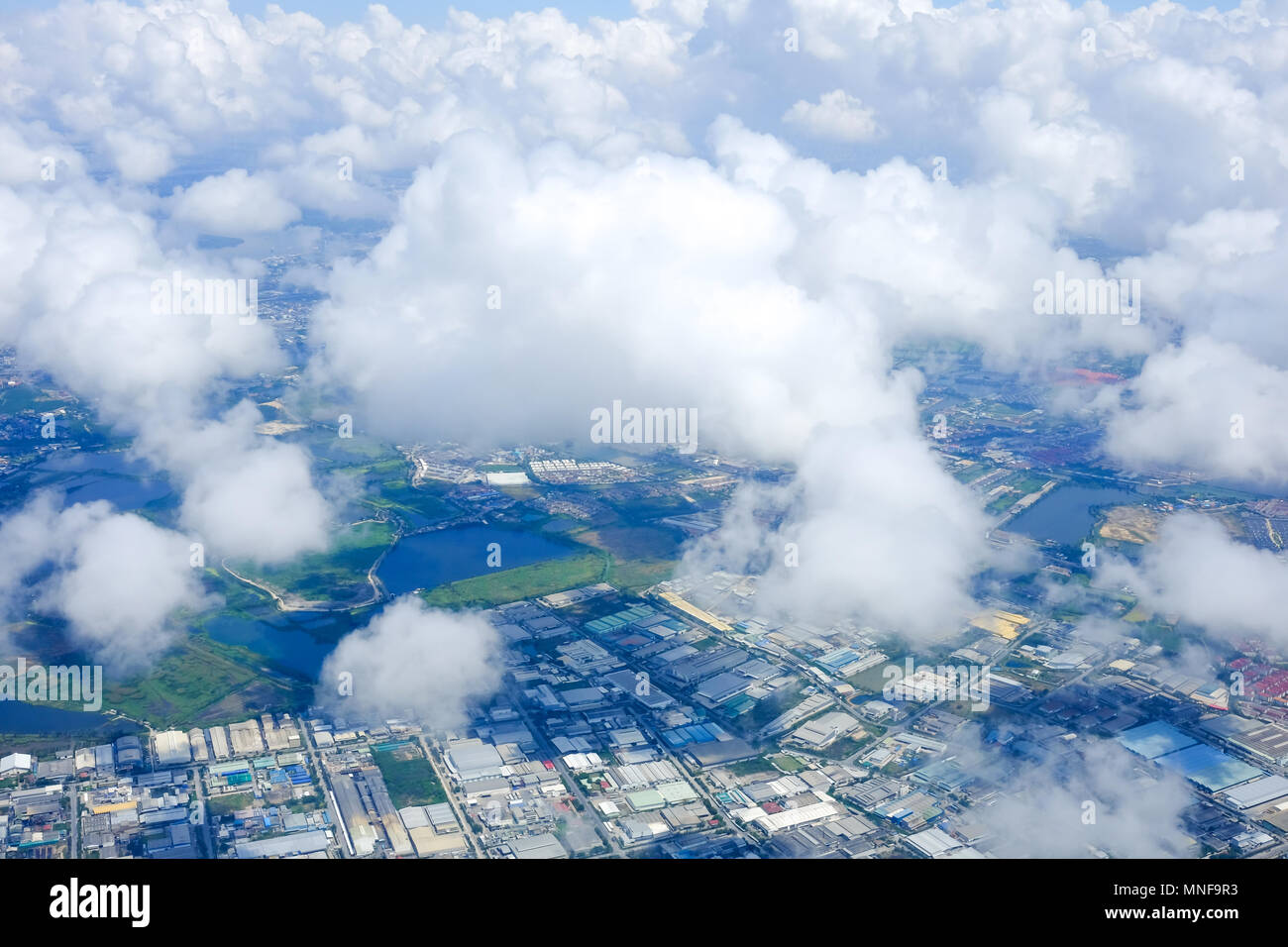 Looking throung airplane window above the clouds and the city below is ...