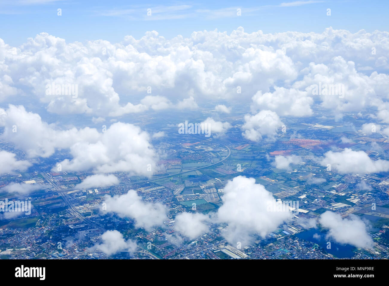 Looking throung airplane window above the clouds and the city below is ...