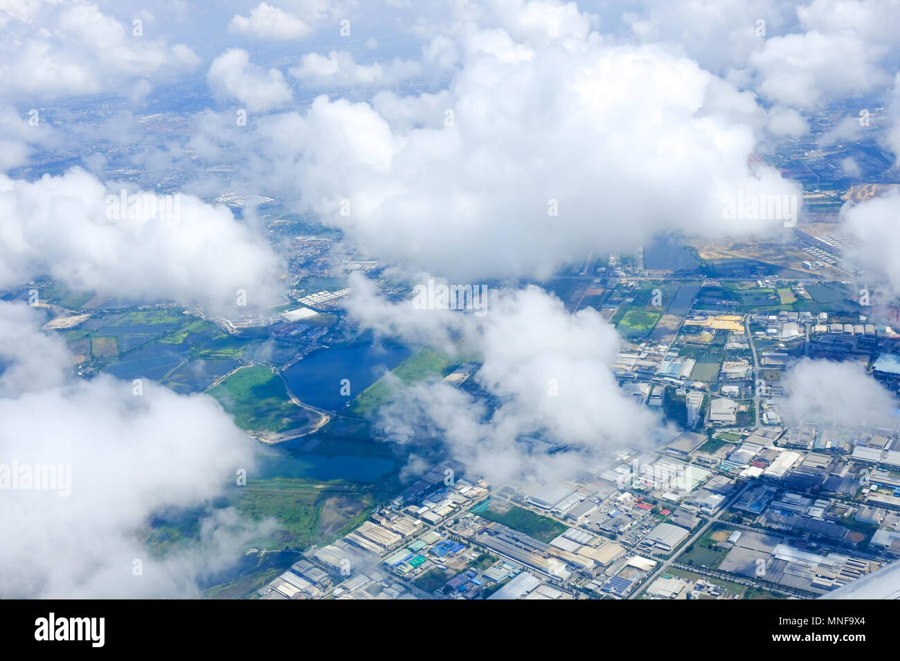 Looking throung airplane window above the clouds and the city below is ...