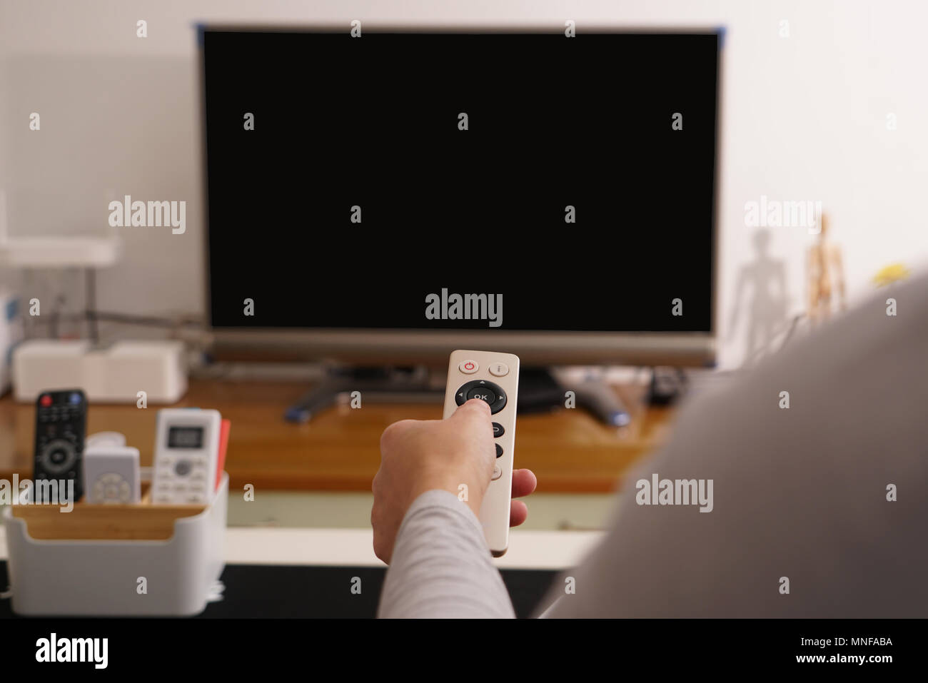 a women hand hold the remote control of the TV box in the living room ...