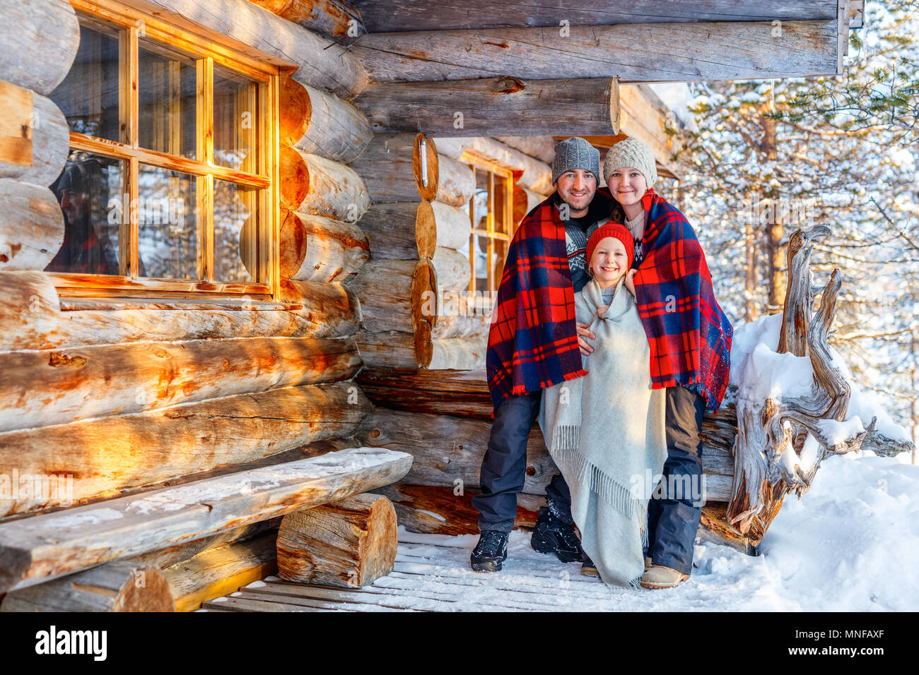 Family with child outdoors on beautiful winter day in front of log ...