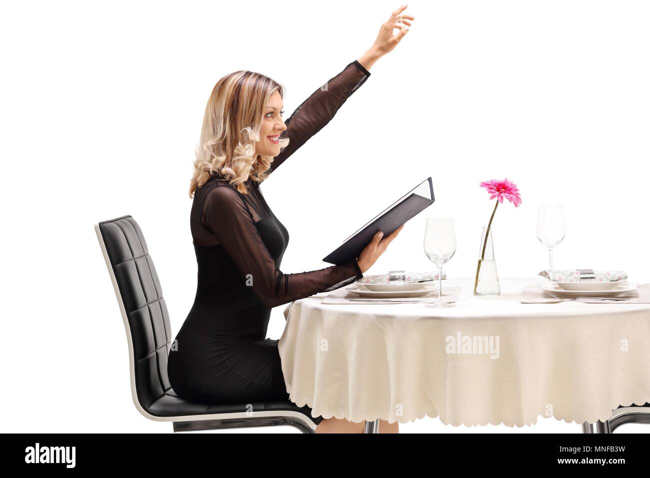 Young woman seated at a restaurant table calling the waiter isolated on ...
