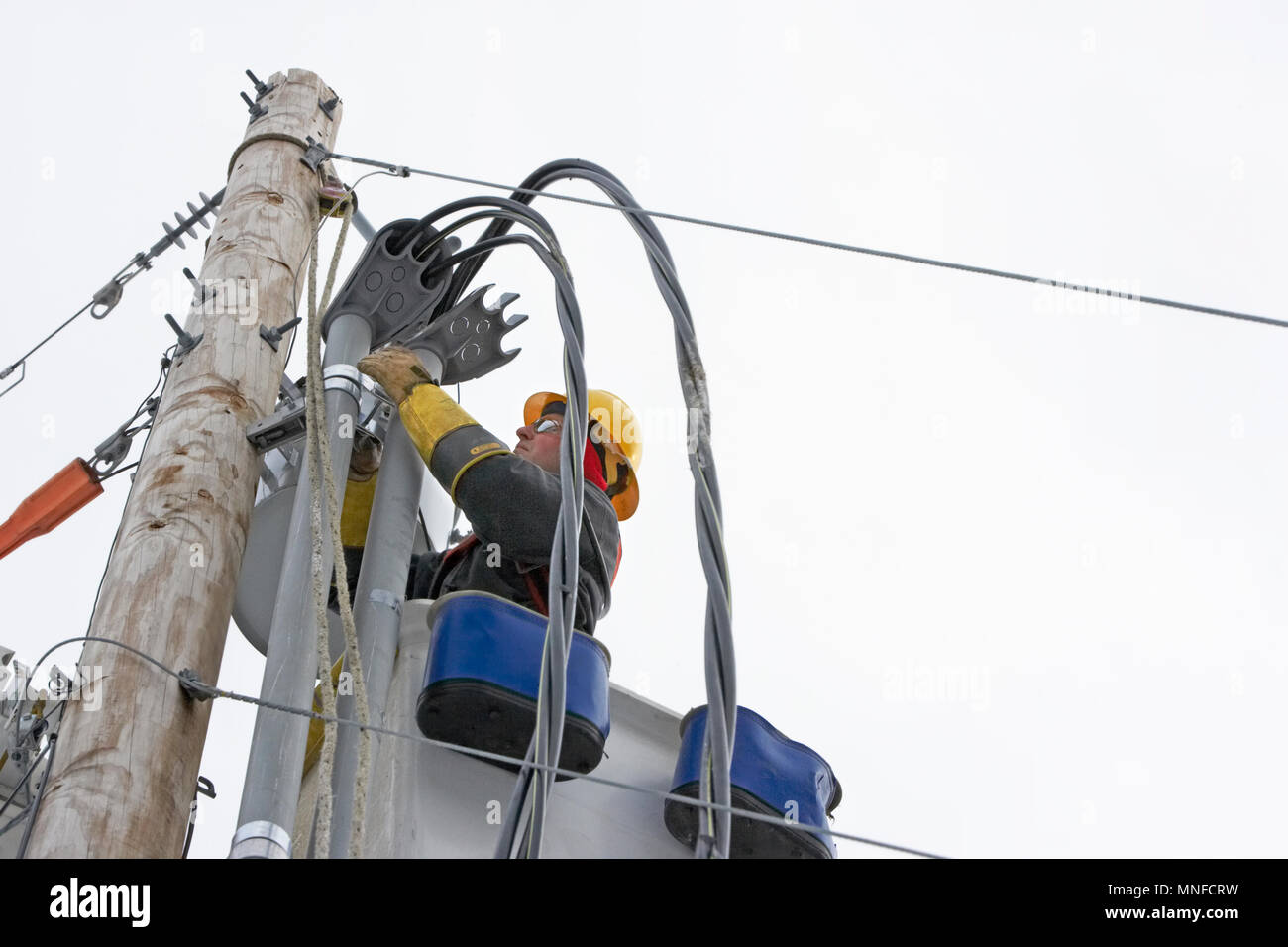 Utility company line man working from a bucket lift to repair and ...