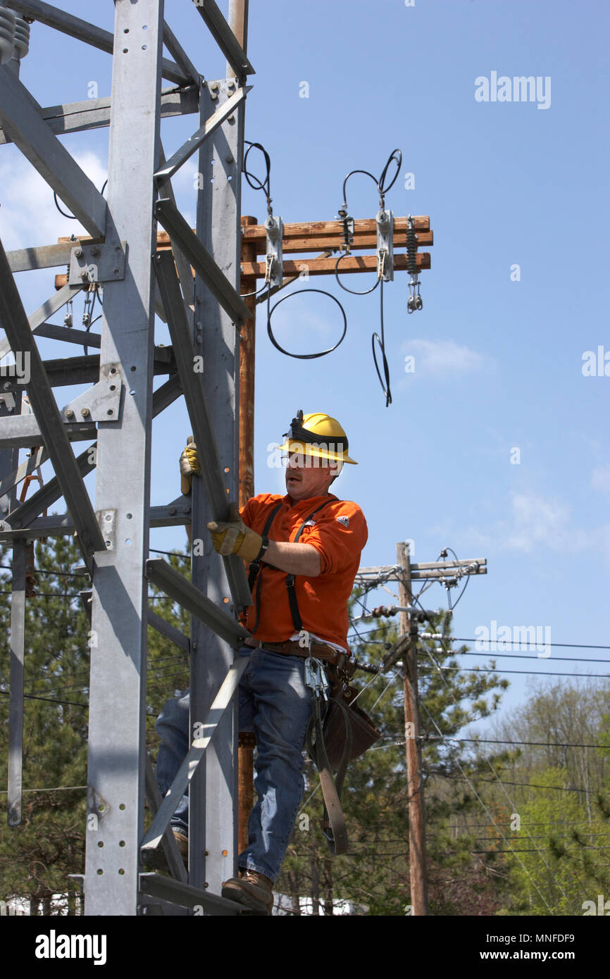 Utility workman wearing safety harness and hardhat installing new ...