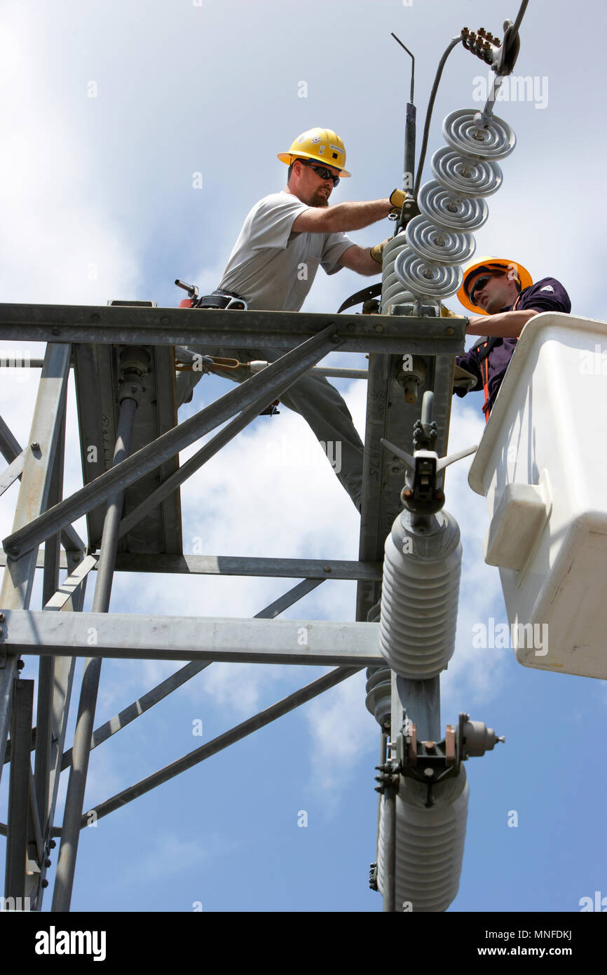Utility workmen wearing hardhat installing new equipment on an ...