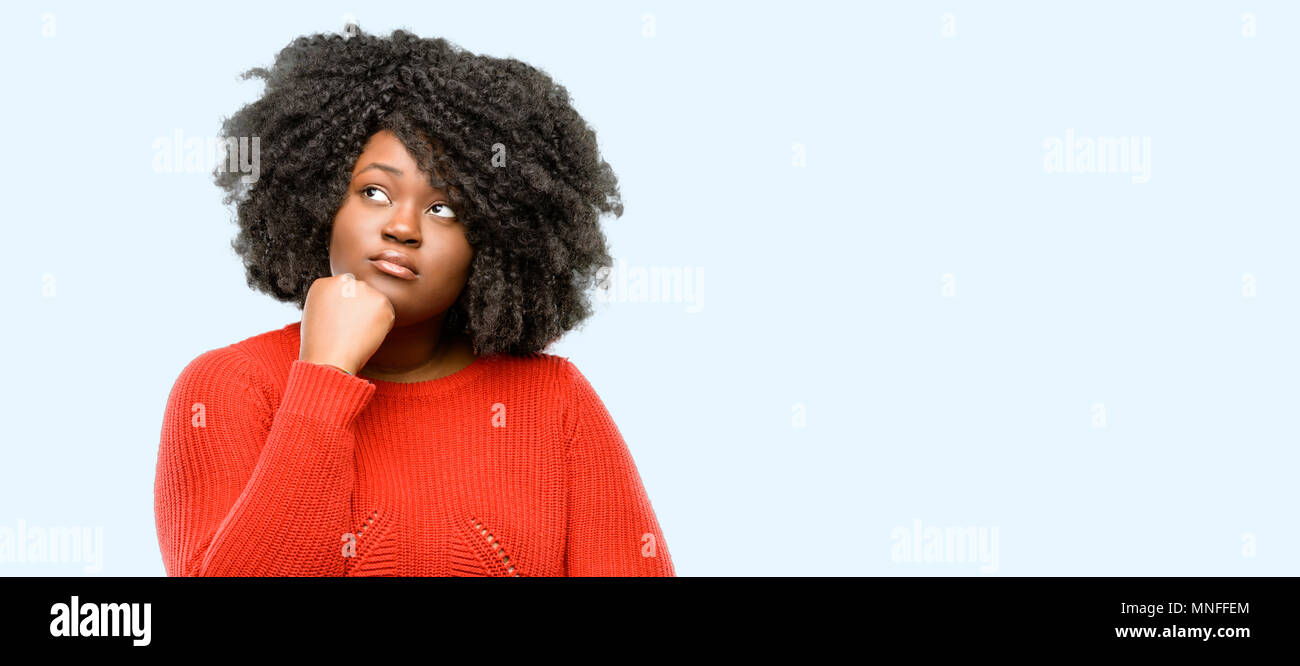 Beautiful african woman thinking and looking up expressing doubt and ...