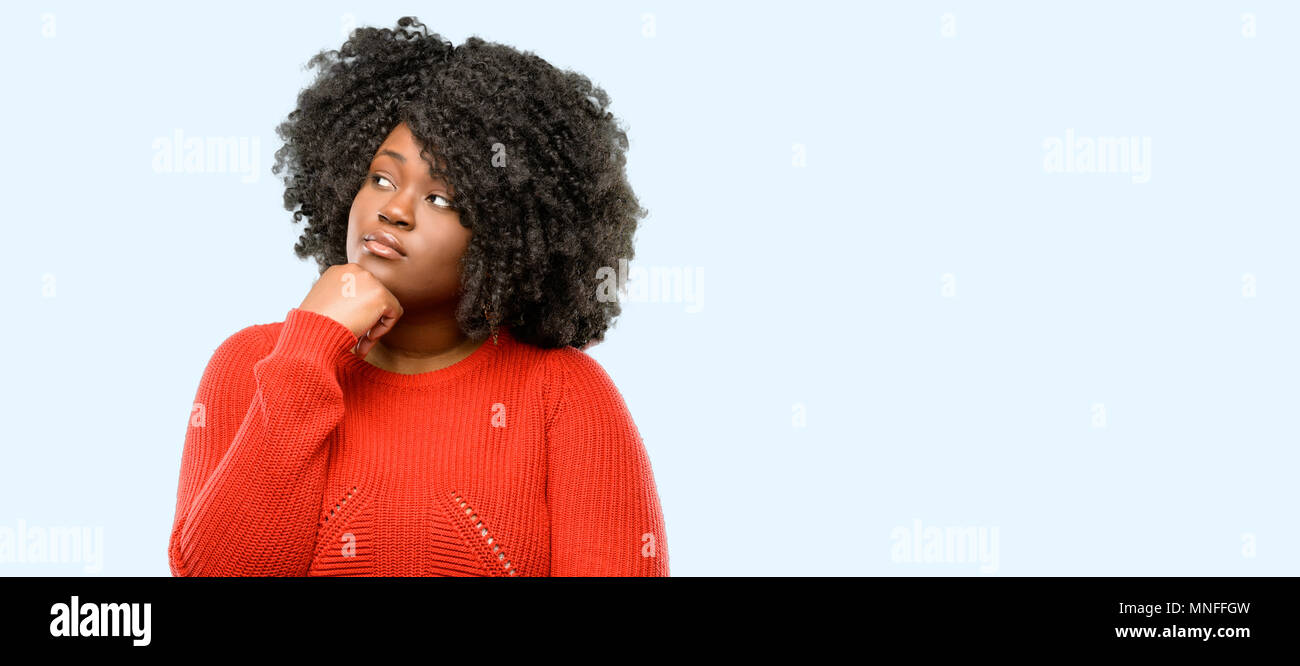Beautiful african woman thinking and looking up expressing doubt and ...