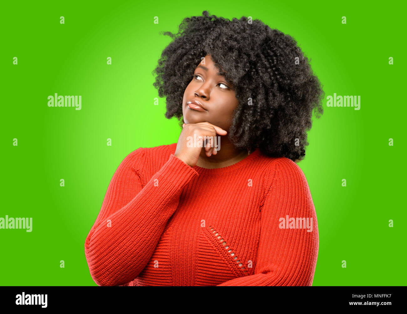 Beautiful african woman thinking and looking up expressing doubt and ...