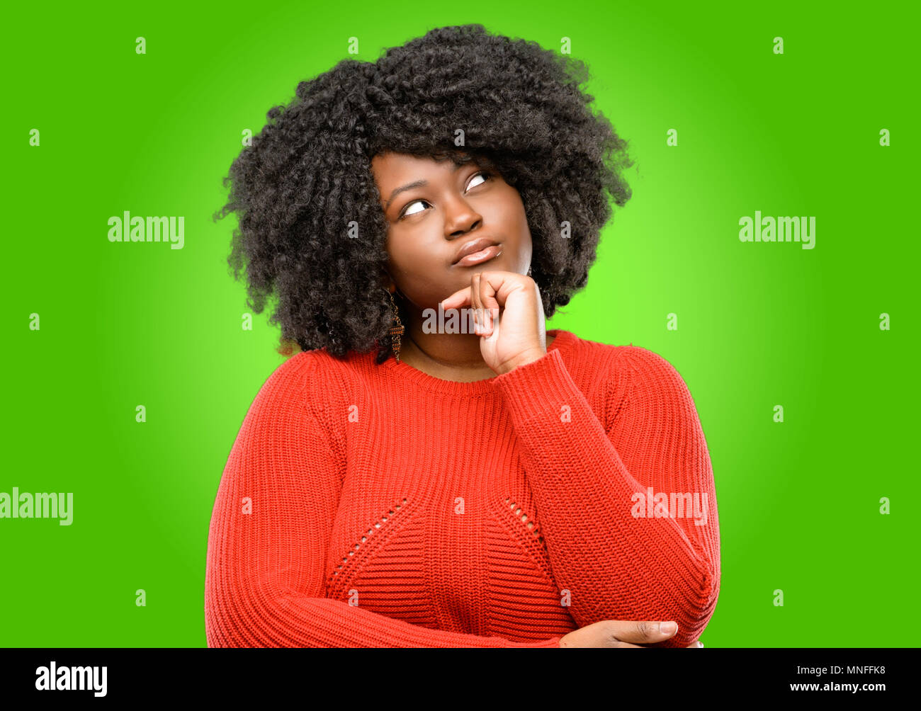 Beautiful african woman thinking and looking up expressing doubt and ...
