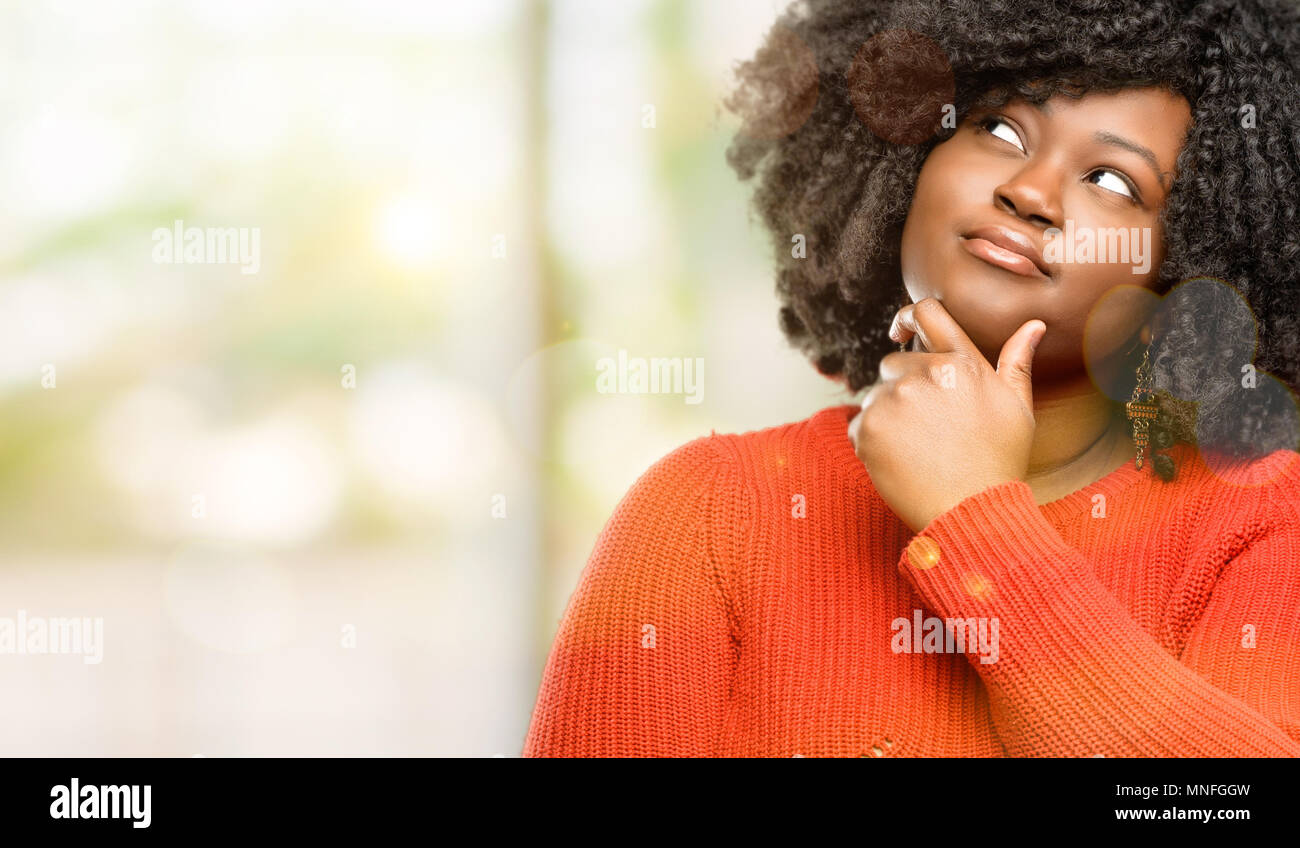Beautiful african woman thinking and looking up expressing doubt and ...