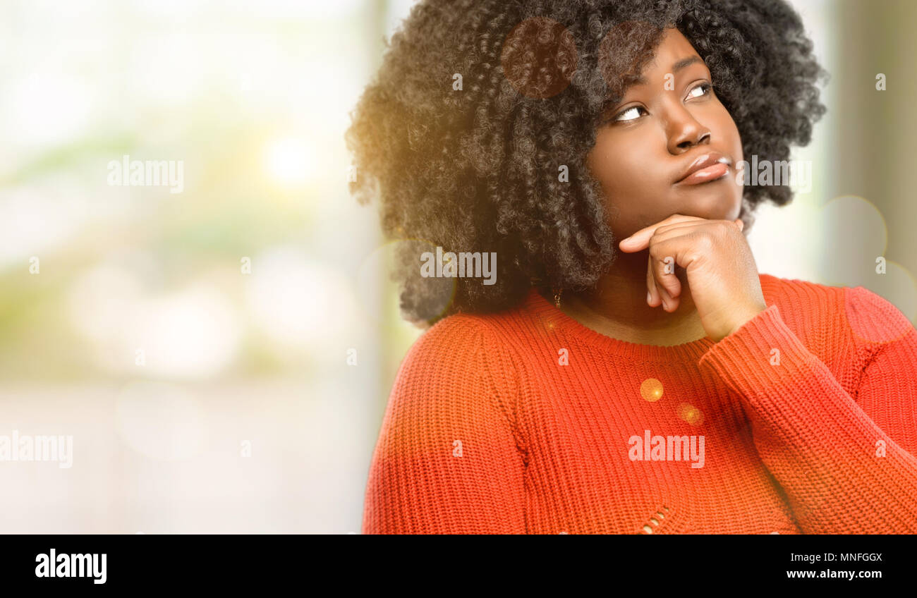 Beautiful african woman thinking and looking up expressing doubt and ...