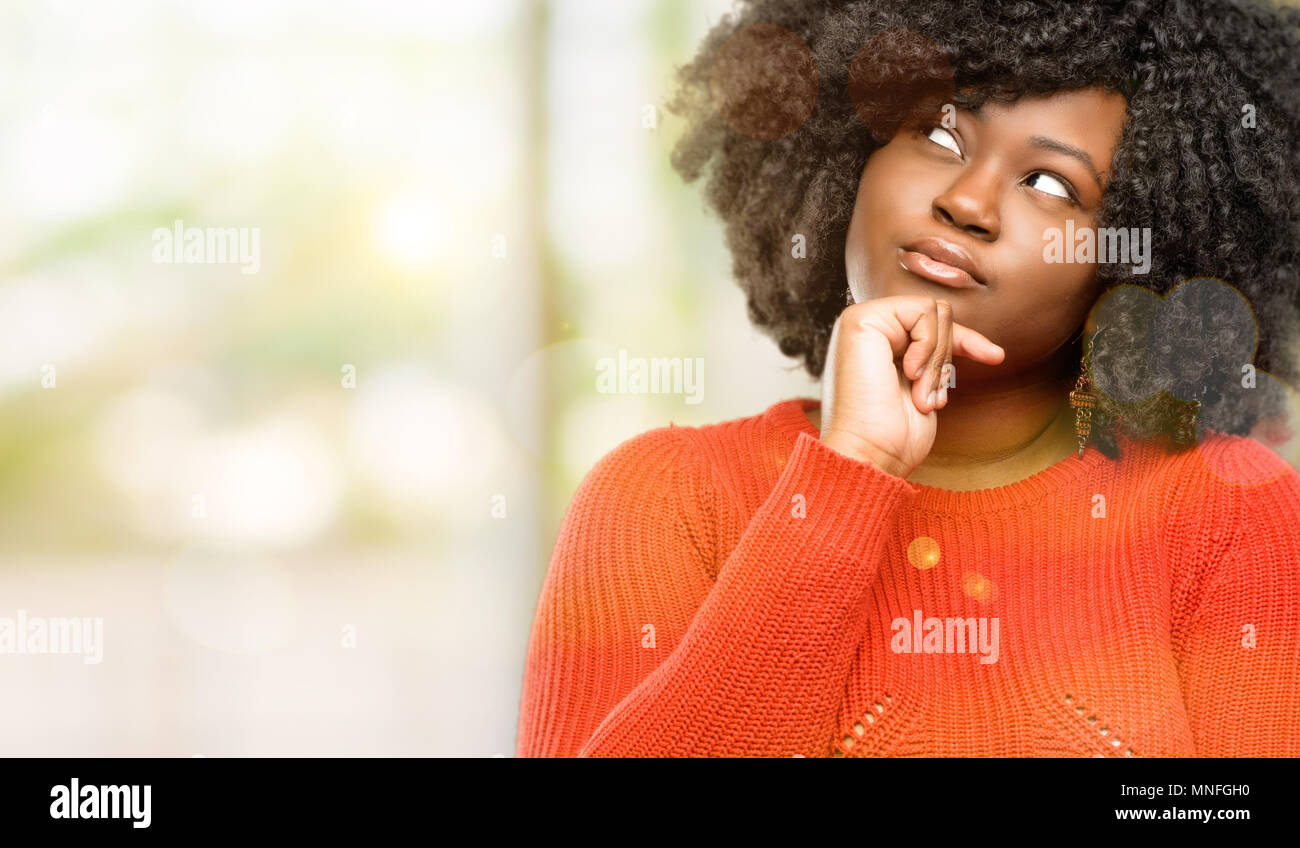 Beautiful african woman thinking and looking up expressing doubt and ...